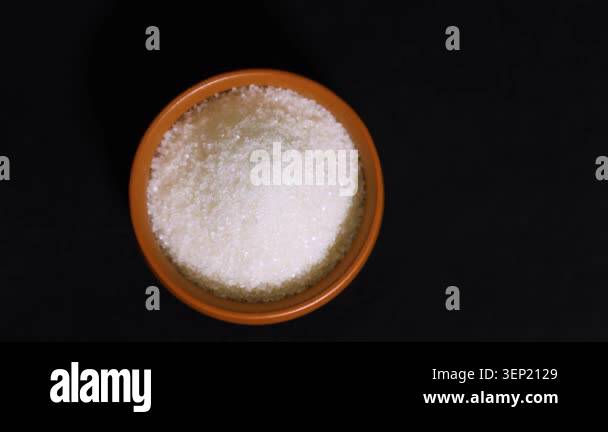 refined white sugar crystals in ceramic bowl isolated on black ...