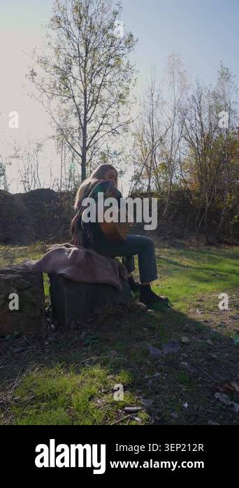 Blonde woman playing string guitar outdoors in autumn forest. Concept ...