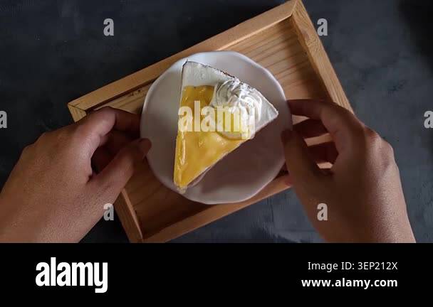 Hands putting plate with slice of lemon blueberry cake on wooden tray ...