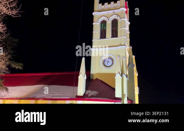 illuminated gothic church tower at night with clock face and ...