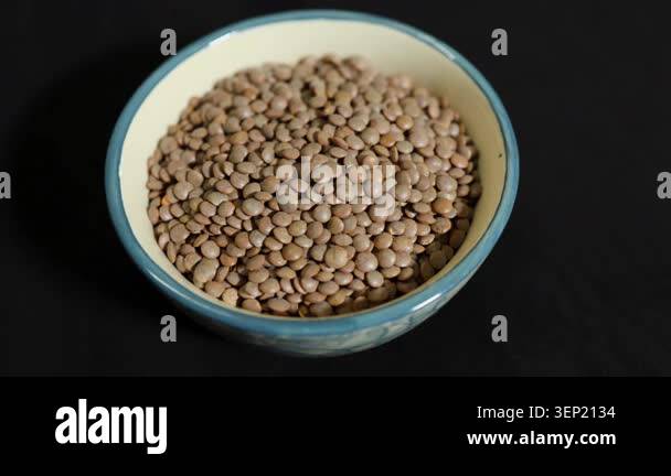 raw brown lentils in ceramic bowl isolated on black background Stock ...