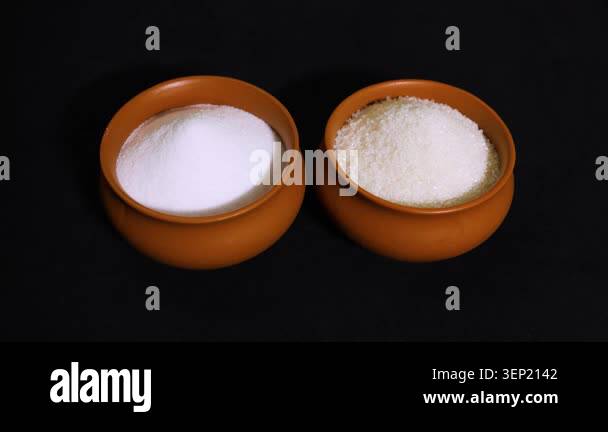 white sugar and table salt in clay bowls isolated on black background ...