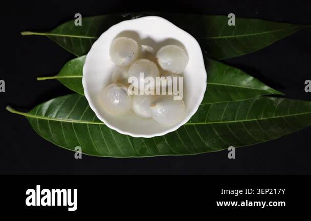 peeled lychee fruit in white bowl placed on fresh green leaves Stock ...