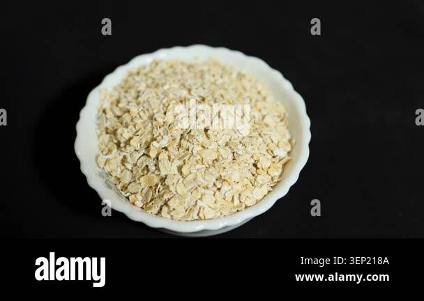 rolled oats in white ceramic bowl isolated on black background healthy ...
