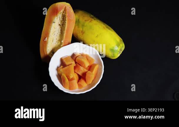 fresh papaya pieces in bowl alongside whole ripe fruit rich in vitamins ...