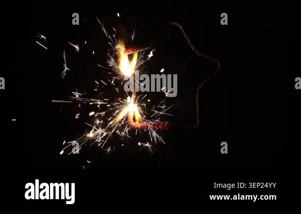Star shaped sparkler burning with bright golden sparks on black ...