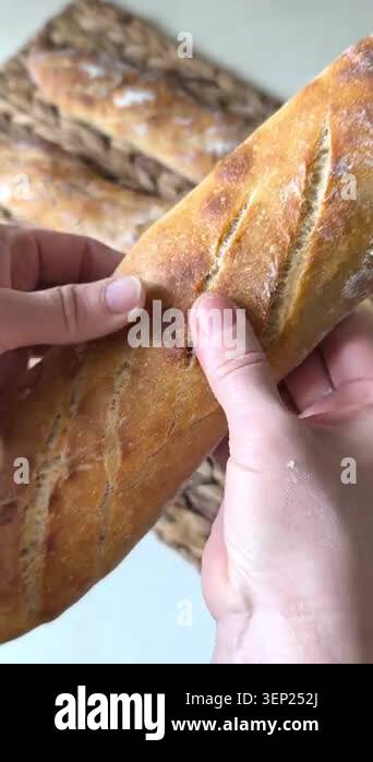 Fresh baguette held by hands against bakery background with crispy ...