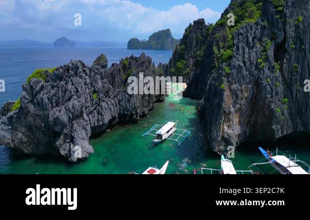 Tourists enjoying clear turquoise water in a hidden lagoon surrounded ...
