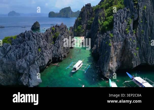 Tourists enjoying clear turquoise water in a hidden lagoon surrounded ...