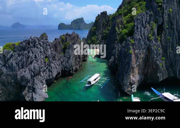 Tourists enjoying clear turquoise water in a hidden lagoon surrounded ...