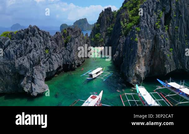 Tourists enjoying clear turquoise water in a hidden lagoon surrounded ...
