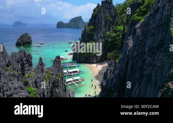 Tourists enjoying clear turquoise water in a hidden lagoon surrounded ...