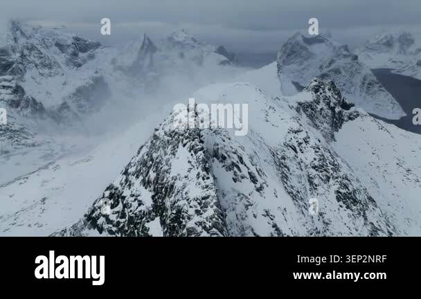 Elevated aerial view of a jagged snow-covered mountain peak slightly ...