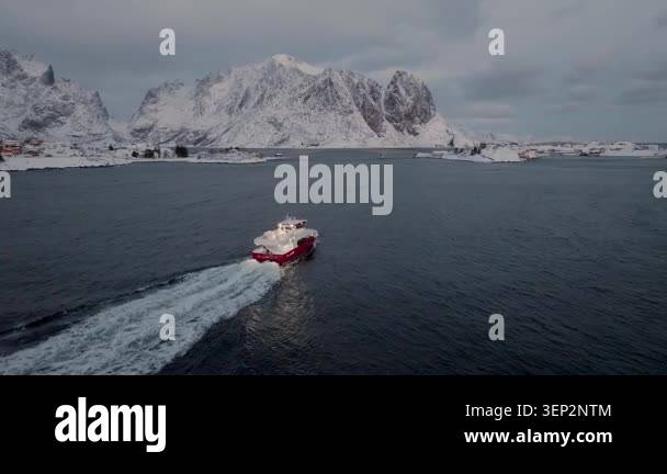 A red-and-white fishing vessel moves away from the camera across dark ...