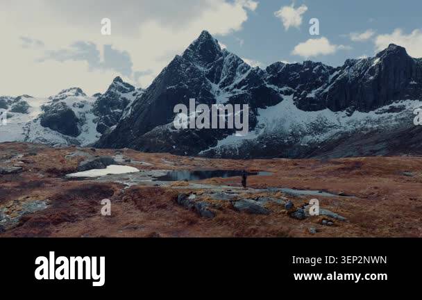 Wide scenic view of dark alpine peaks with patches of snow, a small ...