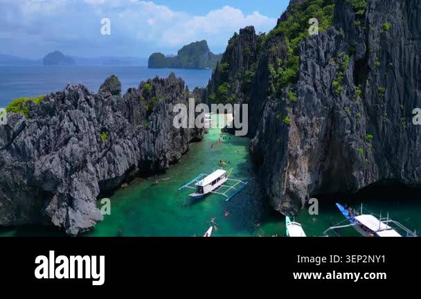 Tourists enjoying clear turquoise water in a hidden lagoon surrounded ...