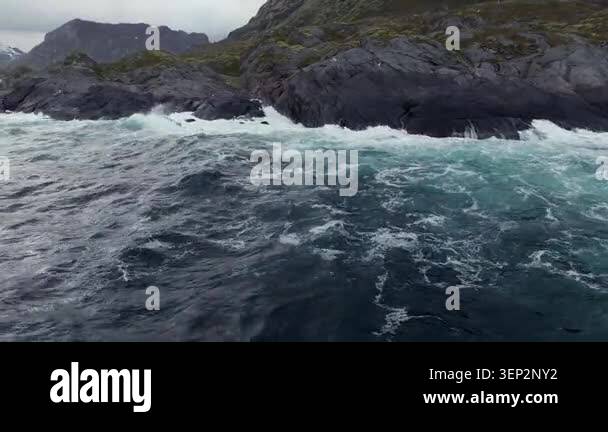 Low vantage view of a rough coastal scene where deep teal, choppy ocean ...