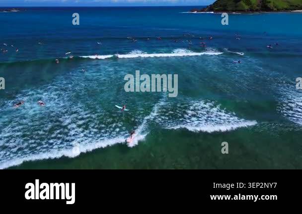 Surfer riding a wave with many other surfers waiting in the distance ...