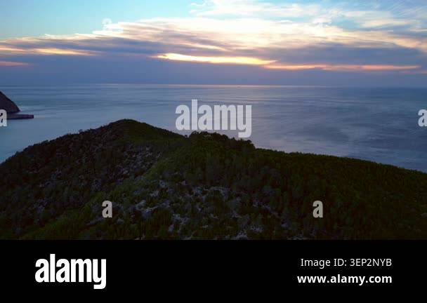 Rolling green hills meeting a calm Mediterranean Sea under a twilight ...