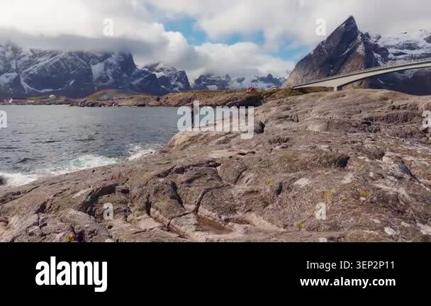 A lone traveler stands on rough granite rocks at the left foreground ...