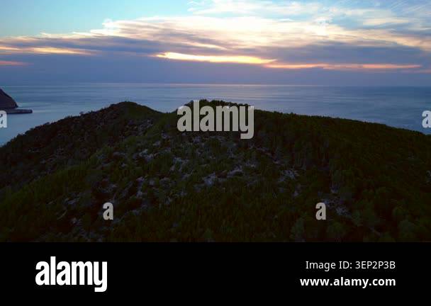 Rolling green hills meeting a calm Mediterranean Sea under a twilight ...