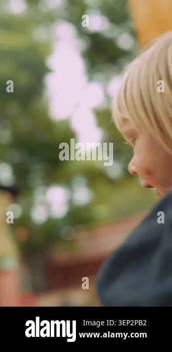 Blonde caucasian toddler walking across playground then squatting to ...