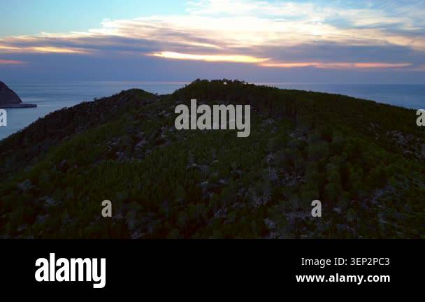 Rolling green hills meeting a calm Mediterranean Sea under a twilight ...