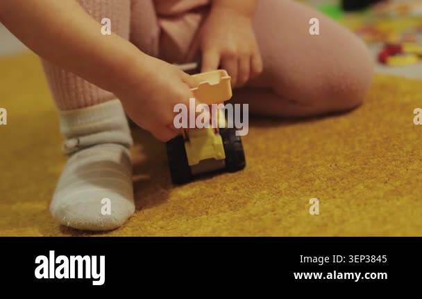 Child hands pushing toy tractor on carpet floor during indoor play ...