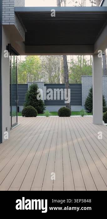 Vertical video. Modern house terrace with wooden decking and pergola ...