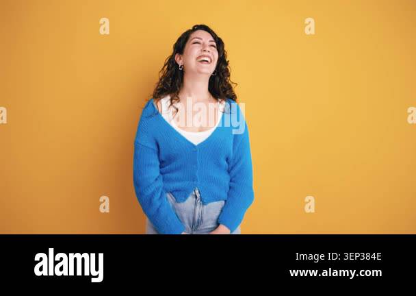 Young beautiful woman with curly hair bursting into laughter. She is ...