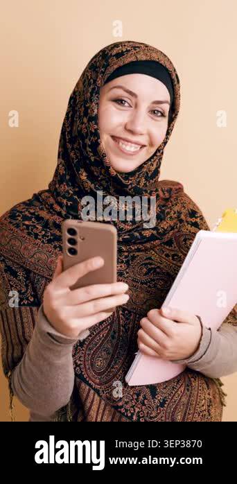 Beautiful young Muslim student wearing a traditional hijab smiling at ...