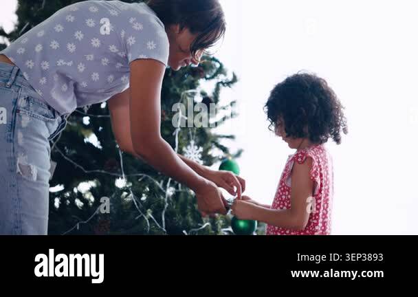 Happy mother and daughter decorating a Christmas tree with green ...