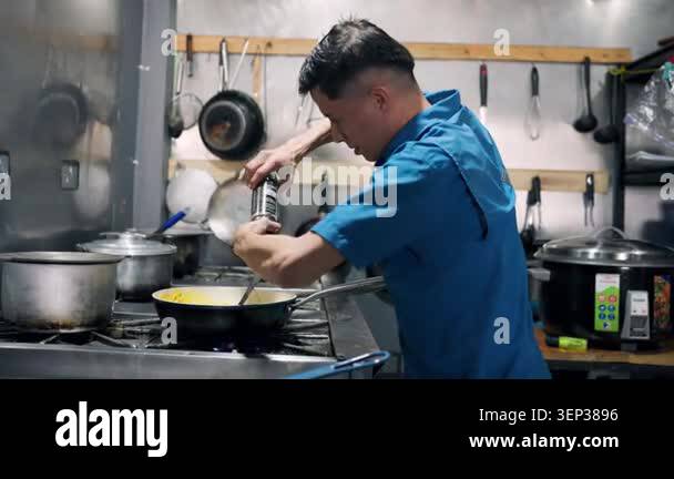 Male cook in a blue uniform seasoning a dish in a pan. Gastronomy ...