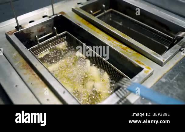 Close up view of french fries sizzling in a commercial deep fryer ...