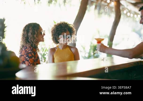 Two beautiful diverse women smiling and toasting with cocktails. A ...