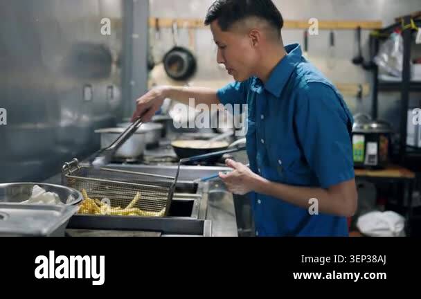 Professional cook preparing crispy french fries in a deep fryer. Man ...
