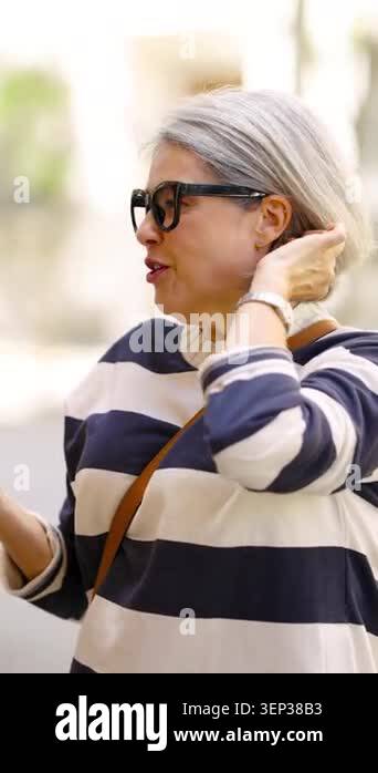 Profile view of an elegant mature woman with grey hair and fashionable ...