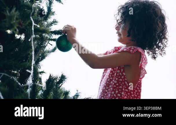 Cute little girl with curly hair smiling while hanging a green glitter ...