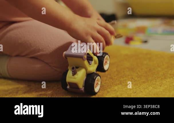 Child hands playing with toy construction vehicle on carpet floor ...
