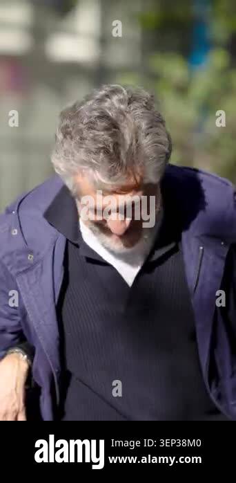 Handsome senior man with gray hair and a beard enjoying a walk outside ...