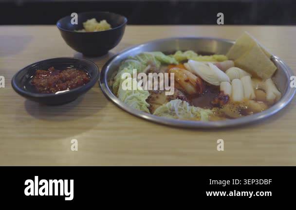Korean hot pot stew served in a metal pot on a wooden table. Includes ...