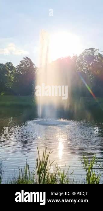 Beautiful water fountain spraying on a lake with the sun reflecting on ...