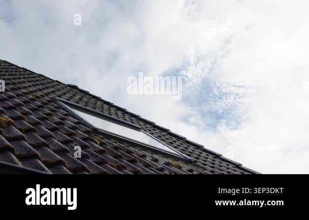 White and grey clouds reflecting in a skylight window on a mossy tiled ...