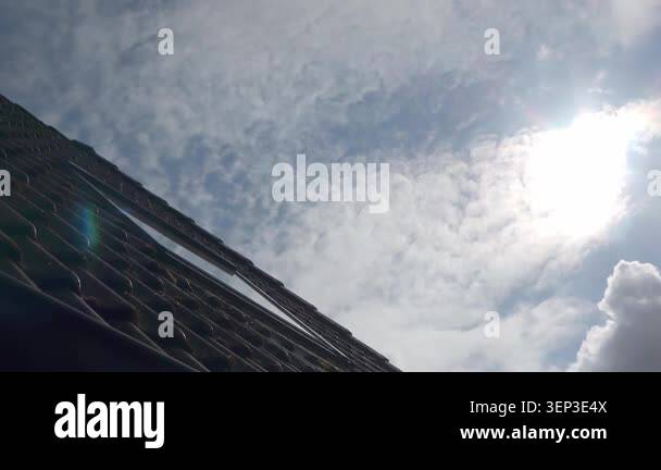 Time lapse Sunny sky with clouds passing over a tiled roof with a ...