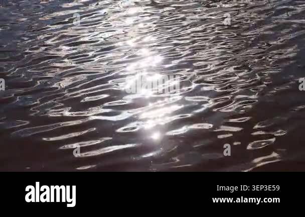 Slow Motion Sun glare reflecting and sparkling on the dark water ...