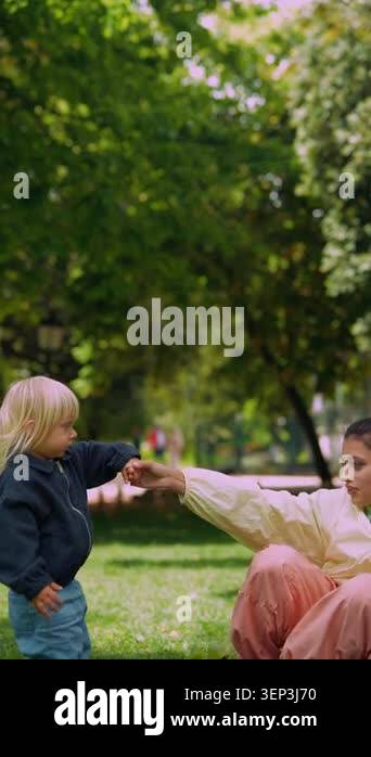 Blonde toddler in park greeted by mentor offering hand friendly smile ...