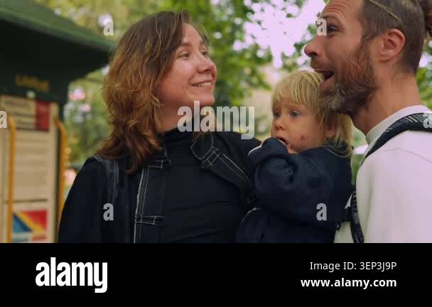 Caucasian family at park kiosk pointing out route, mother smiling ...
