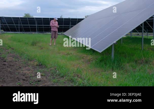 man with solar panels and laptop in the green field. solar panels on ...