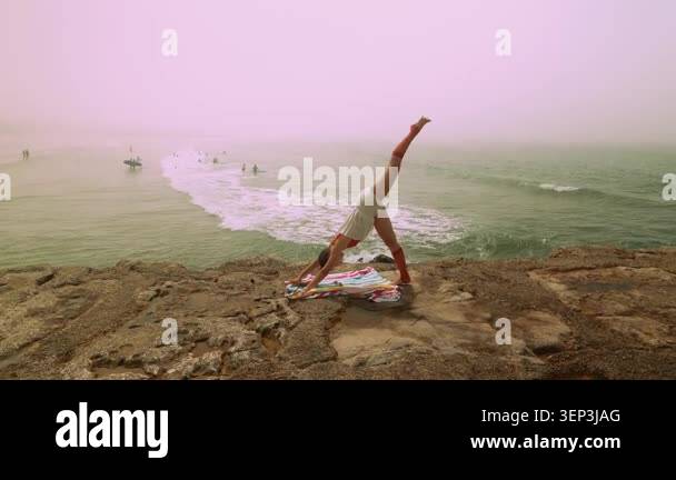 Caucasian athlete transitioning yoga flow on cliff moving from seated ...