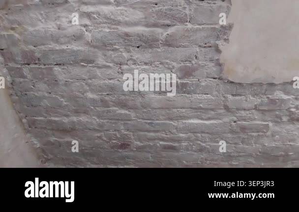 Slow camera tilt of an old white painted brick wall with cracked and ...